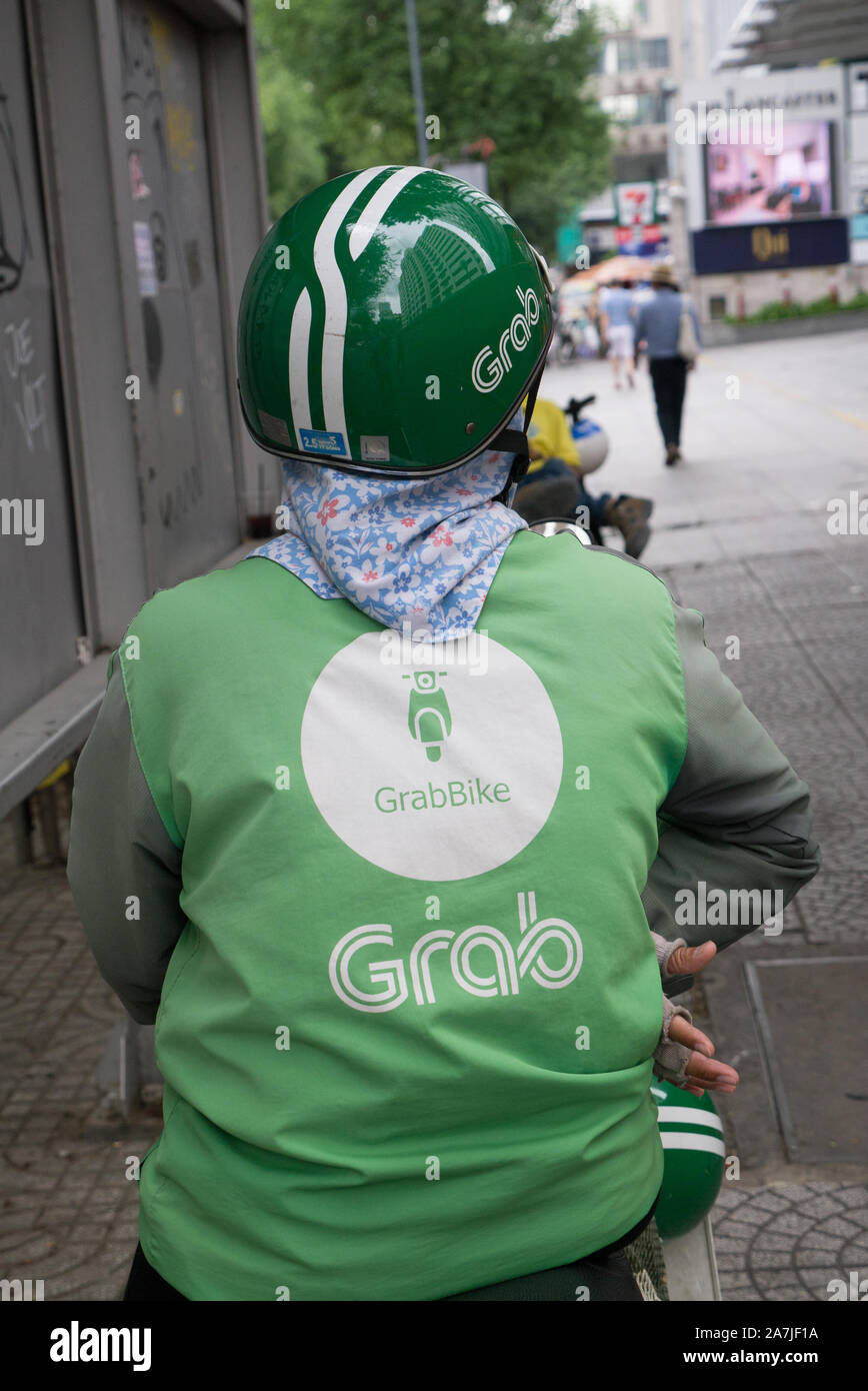 Vertical image of Grab Vietnam motorcycle delivery/taxi driver wearing ...