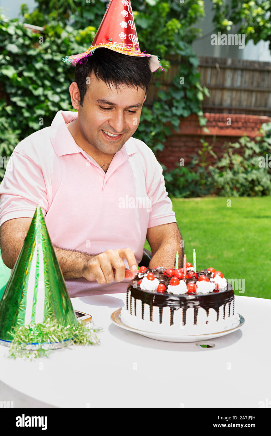 Happy Smiling Adult man cutting the cake at her birthday in-garden of ...