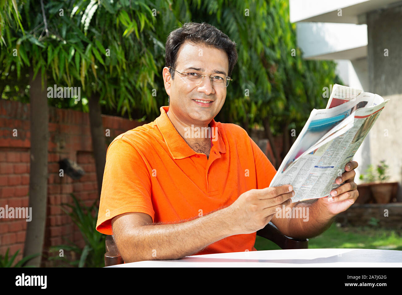 Portrait of Smiling Mid-adult Male Reading Newspaper in-morning in the ...
