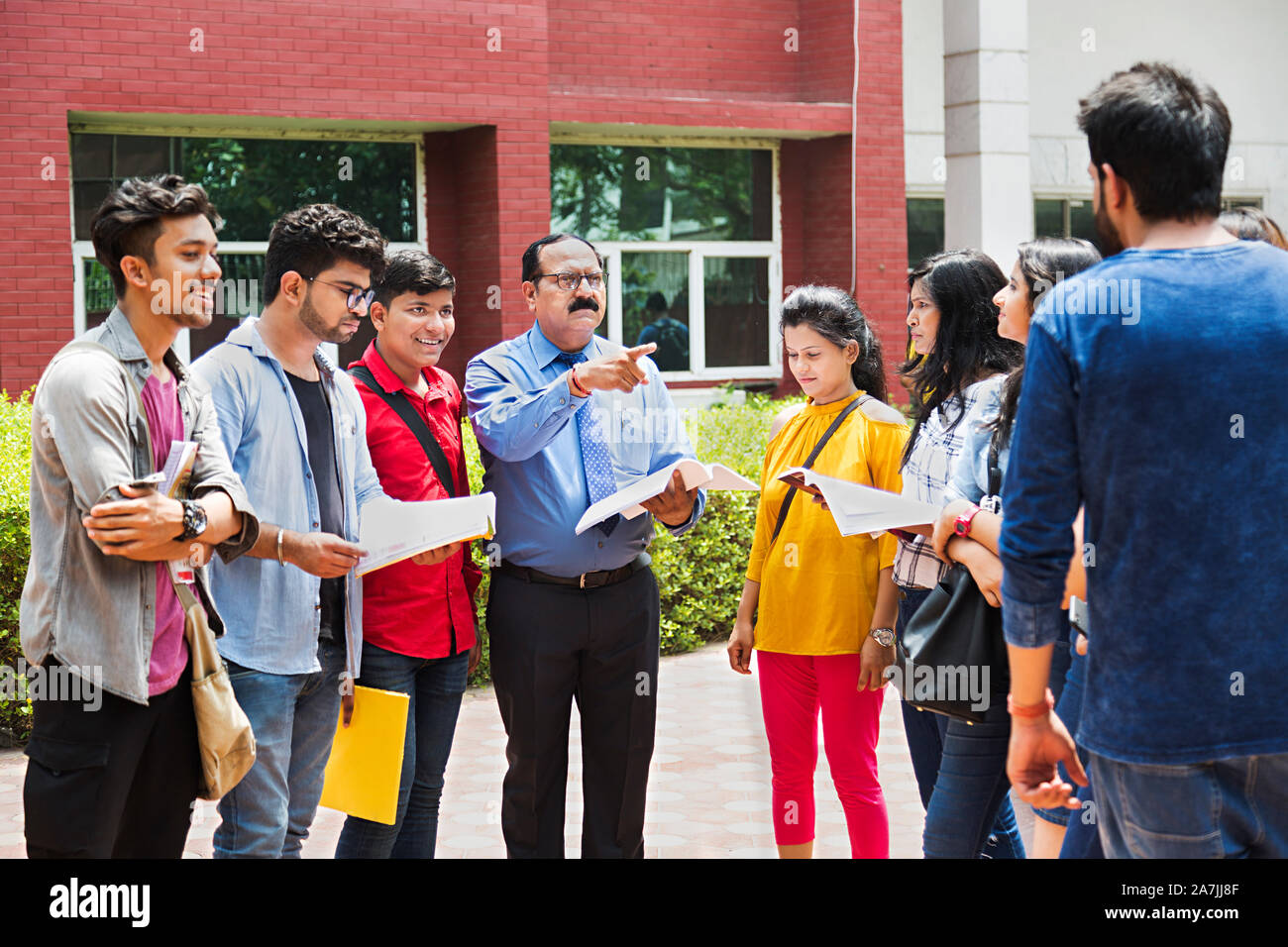 Group Of College Students With Professor Study Book Pointing Question ...