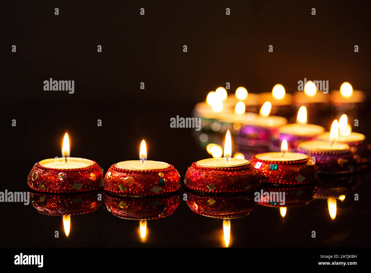 curved line of lit tea lights in the dark background on Diwali Festival ...