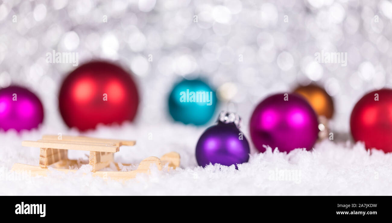 Colorful Baubles and a wooden sledge with snow, white glitter ...