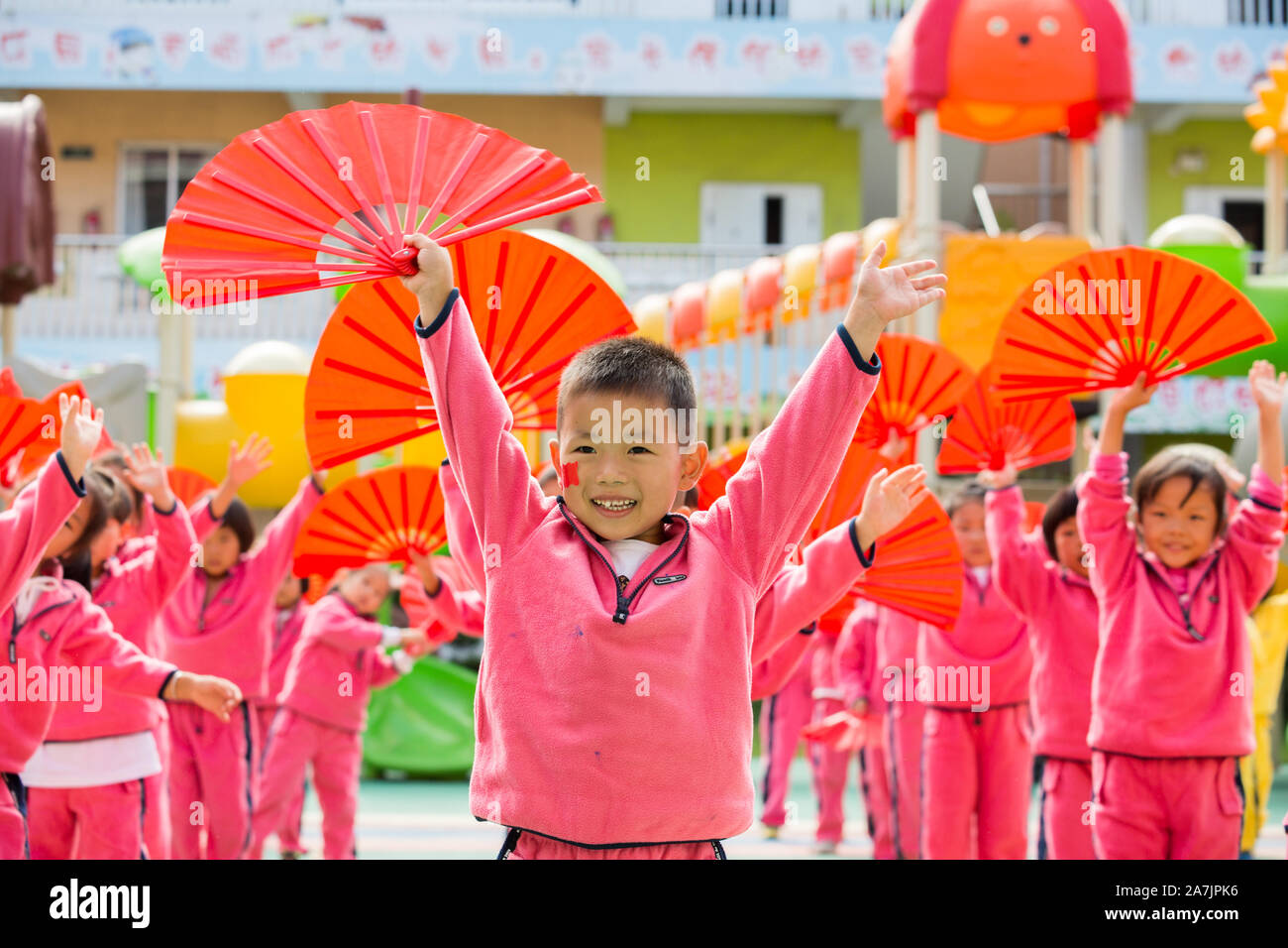 Kindergarten kids do group red fan dance to embrace the upcoming of the ...