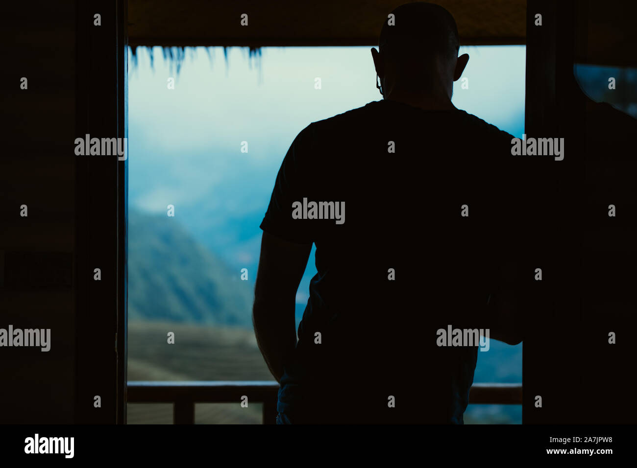 White adult male looking out through a doorway from a cabin over a ...