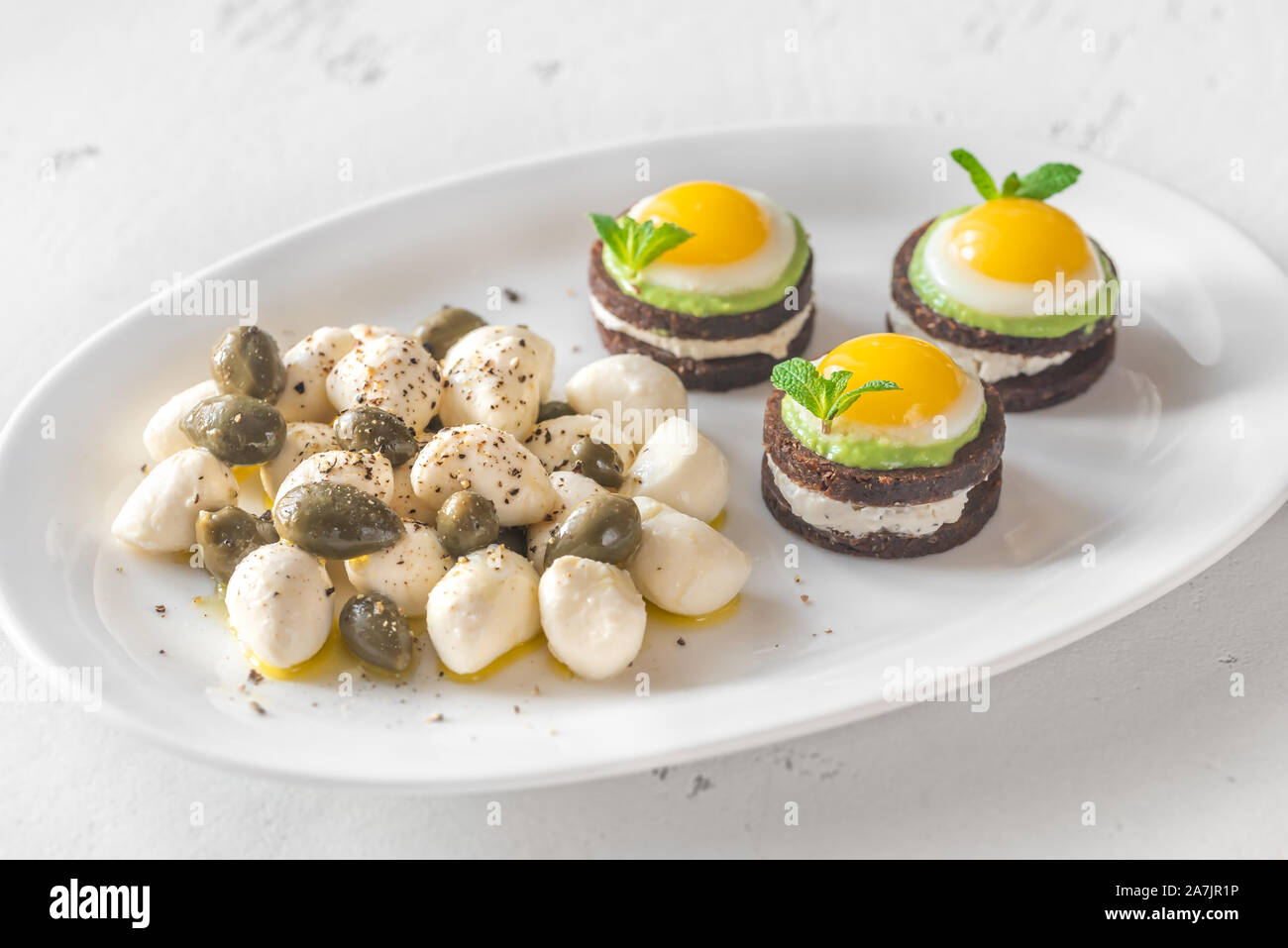 Appetizer with canape, mozzarella and capers on the white plate Stock ...