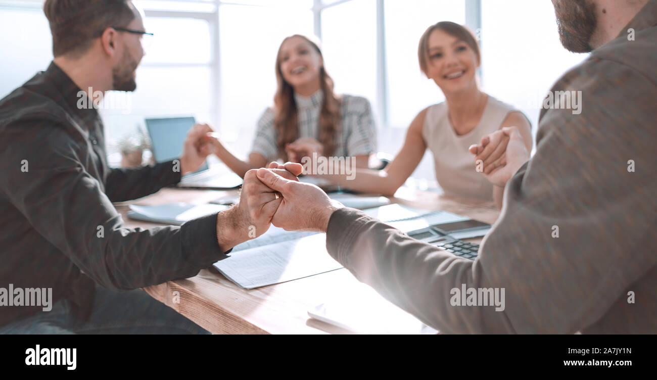 business team sitting at the table and showing their unity Stock Photo ...