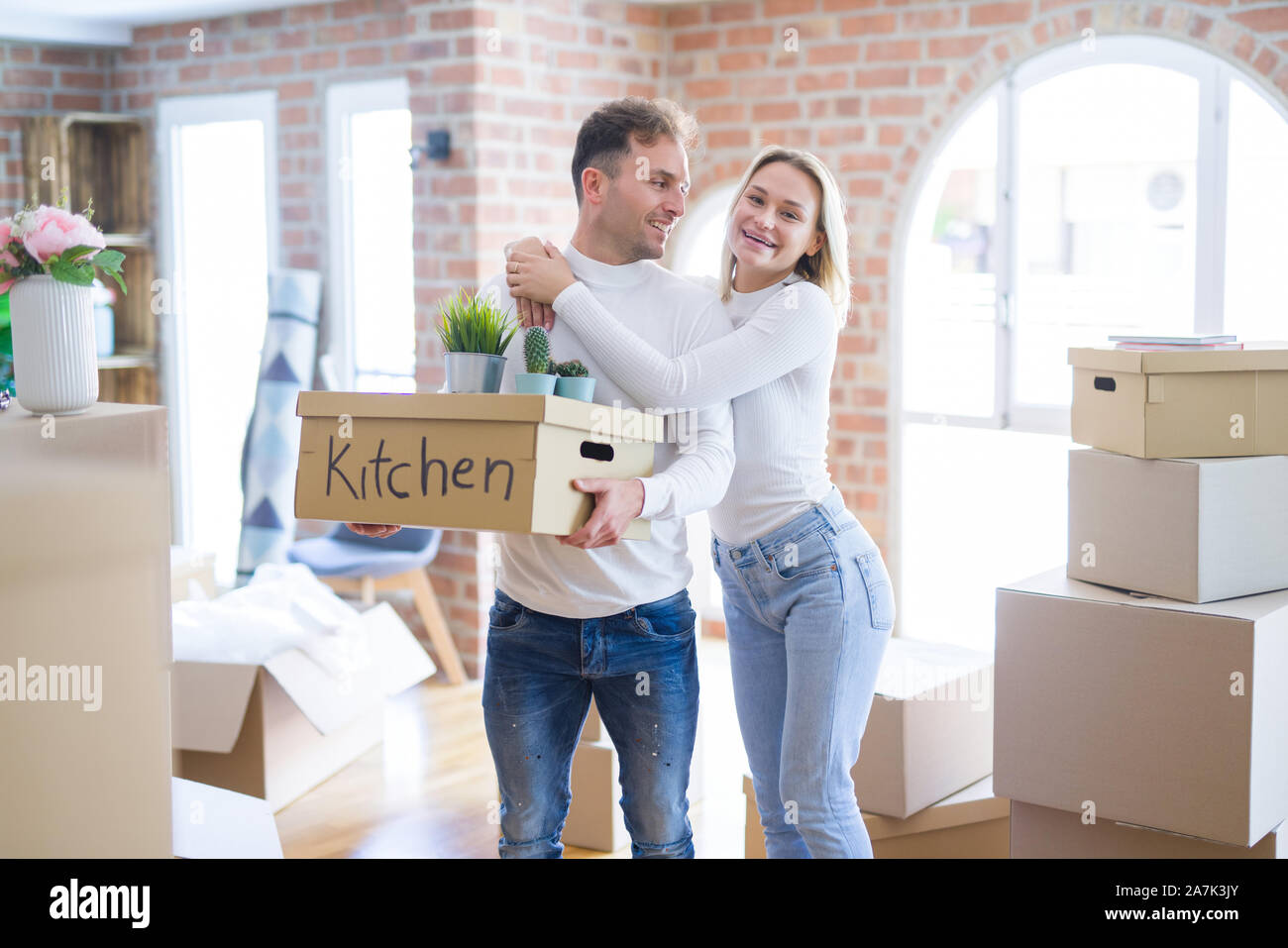 Young beautiful couple moving cardboard boxes at new home Stock Photo ...