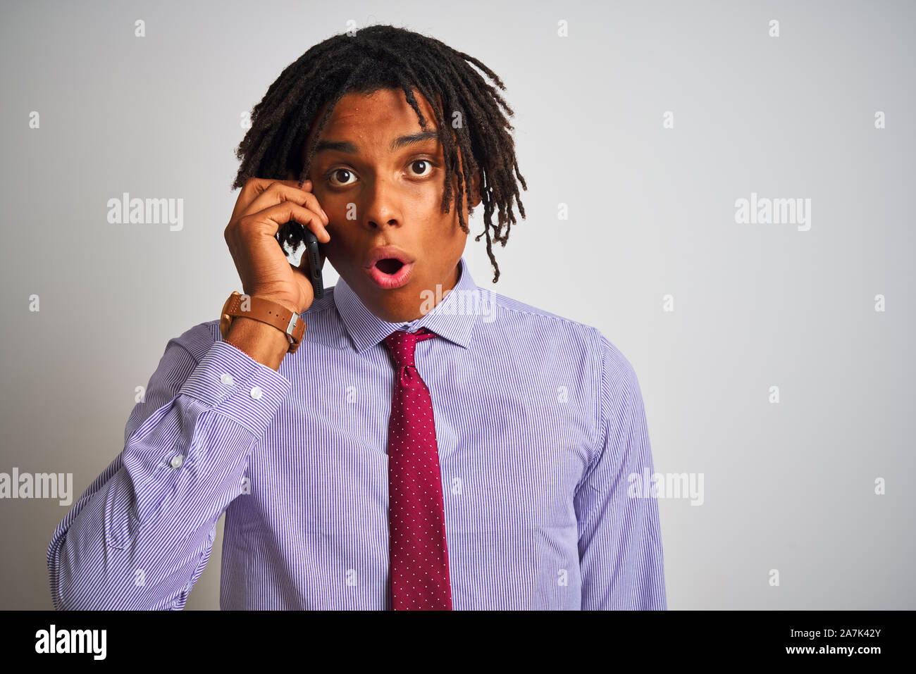 Afro businessman with dreadlocks talking using smartphone over isolated ...