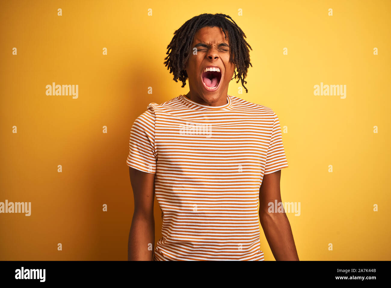 Afro man with dreadlocks wearing striped t-shirt standing over isolated ...
