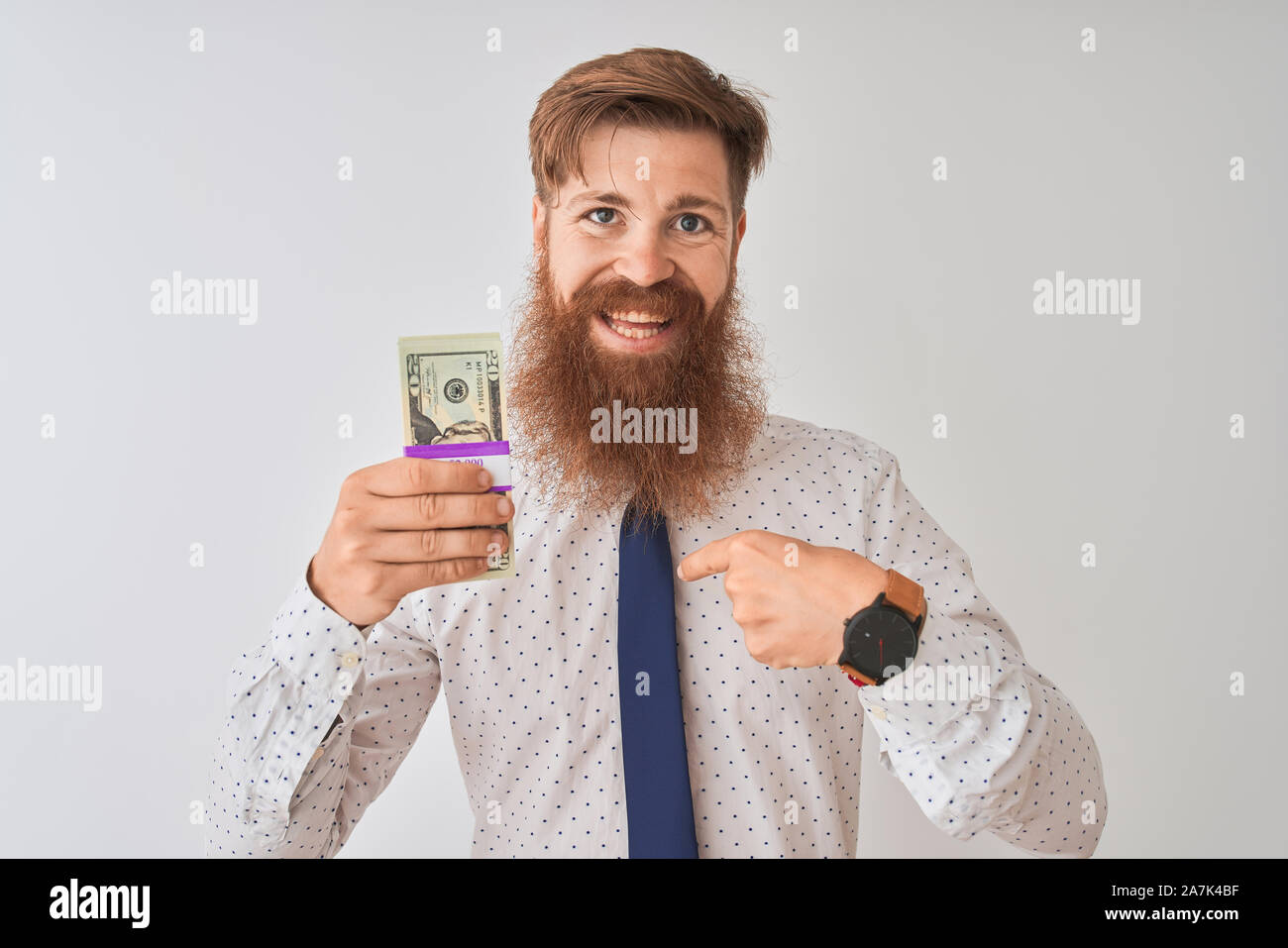 Young redhead irish businessman holding dollars standing over isolated ...