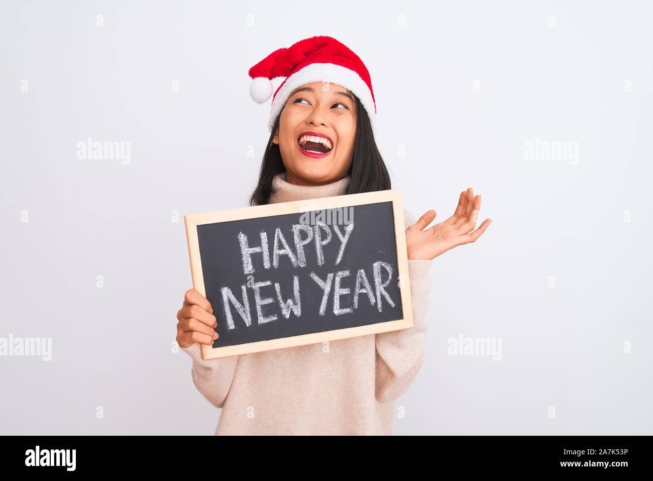 Young chinese woman wearing Santa hat holding blackboard over isolated ...