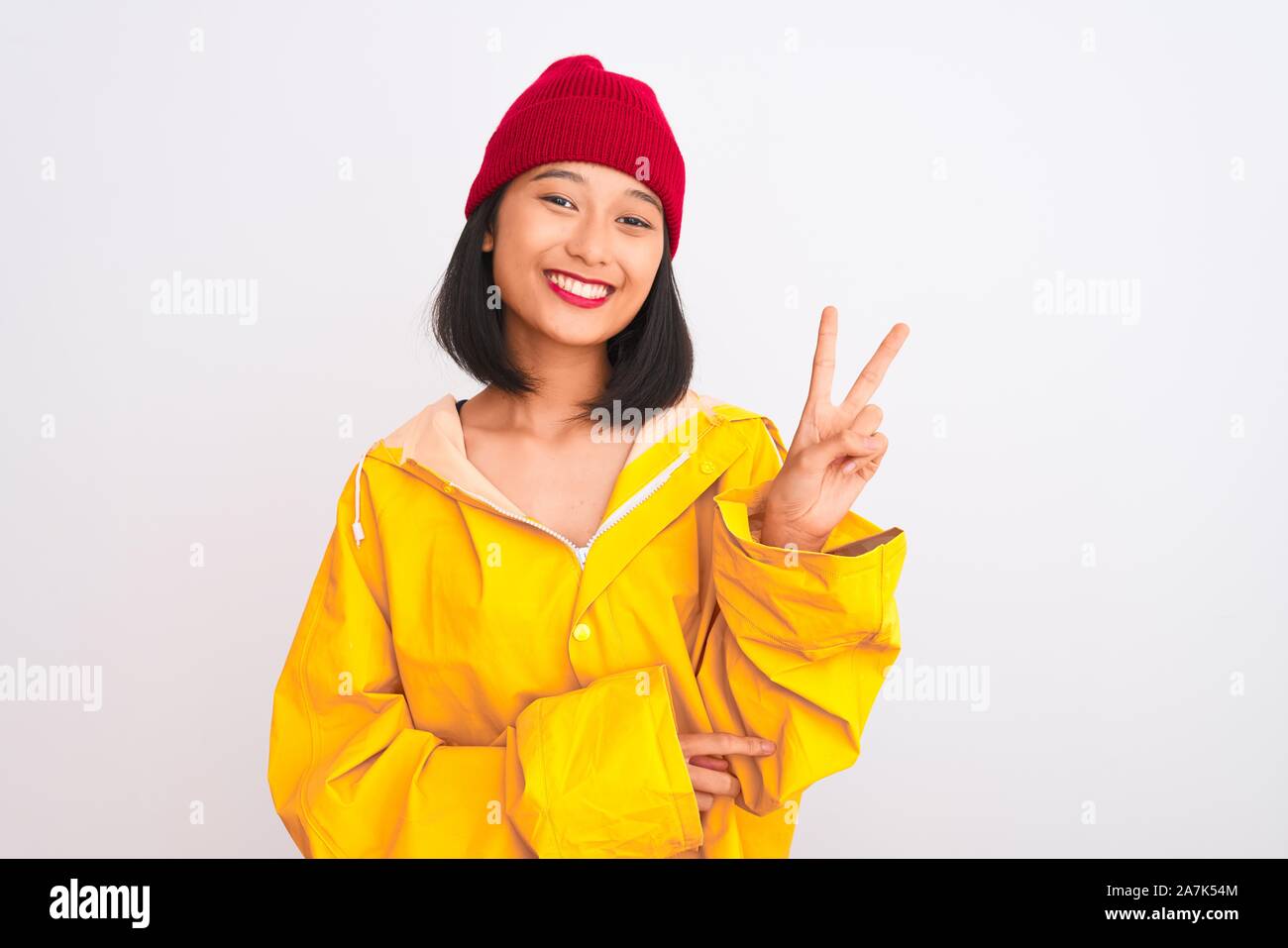 Young beautiful chinese woman wearing raincoat and wool cap over ...