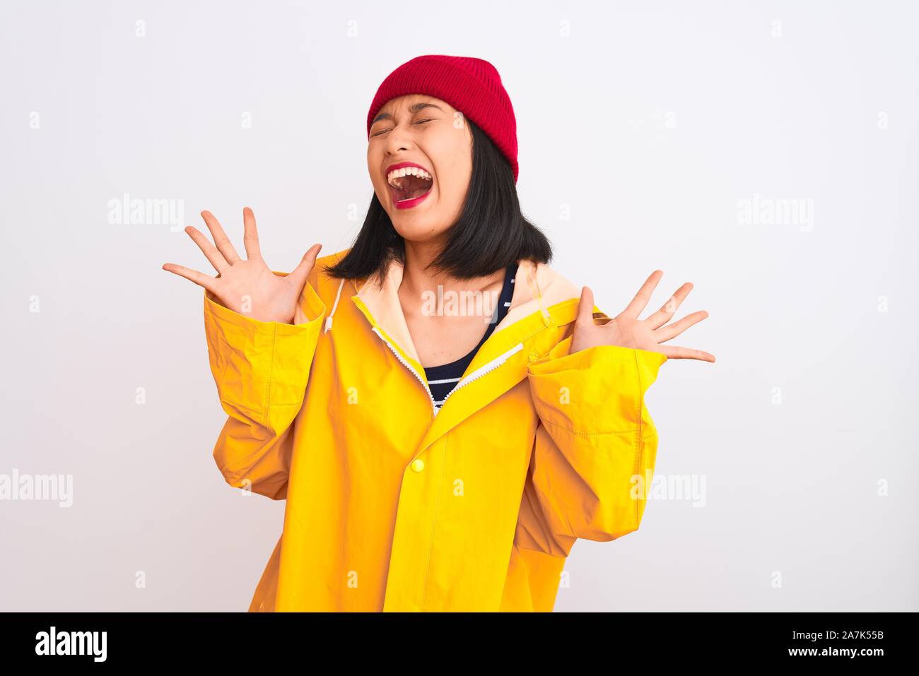 Young beautiful chinese woman wearing raincoat and wool cap over ...
