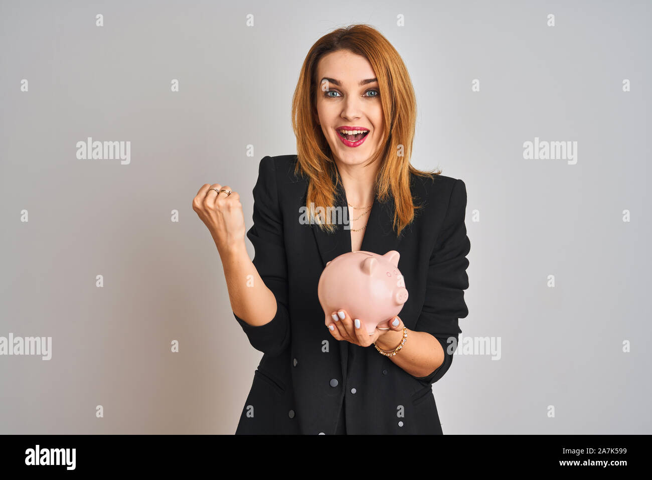Redhead caucasian business woman holding piggy bank over isolated ...