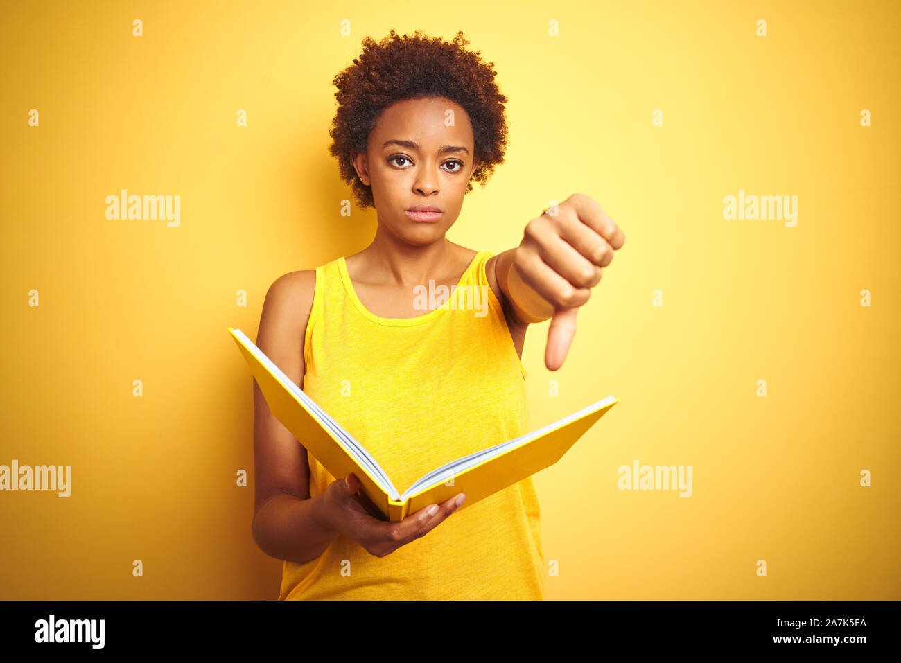 African american woman reading a book over yellow isolated background ...