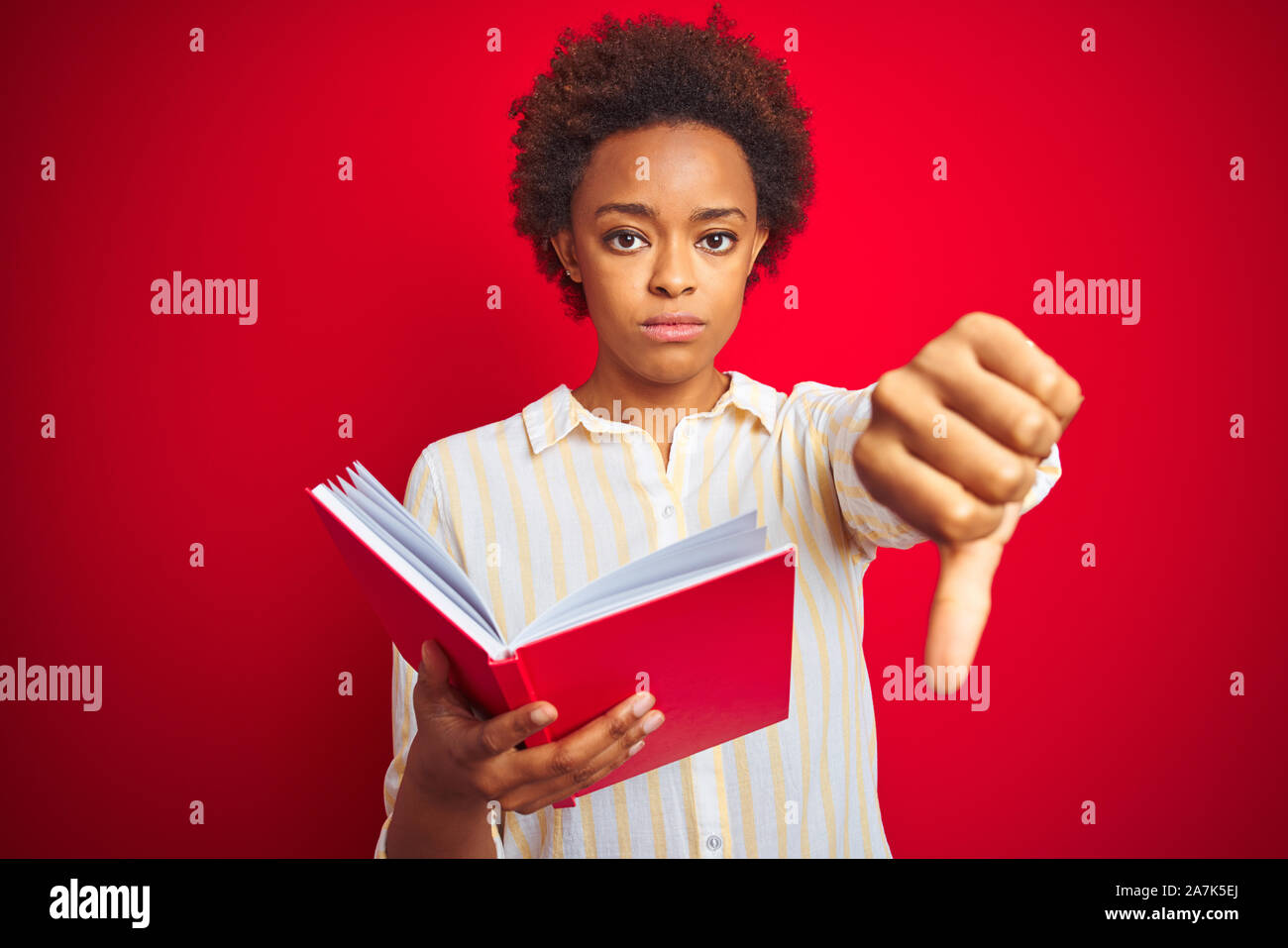 African american woman reading a book over red isolated background with ...