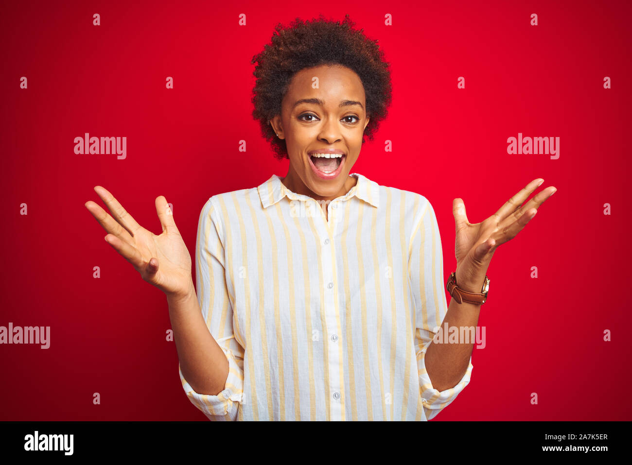 Young beautiful african american woman with afro hair over isolated red ...