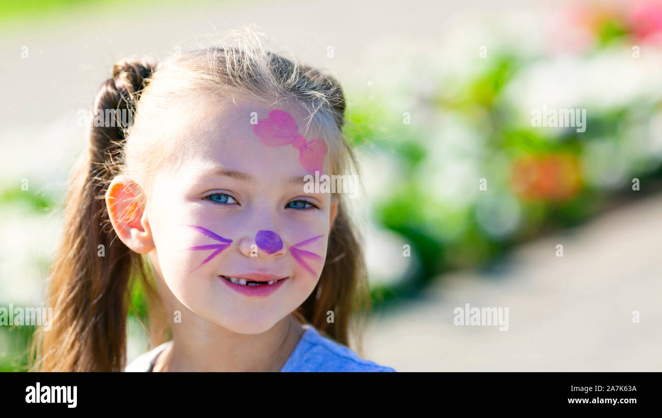 A preschool girl with paints on her face is smiling on street Stock ...