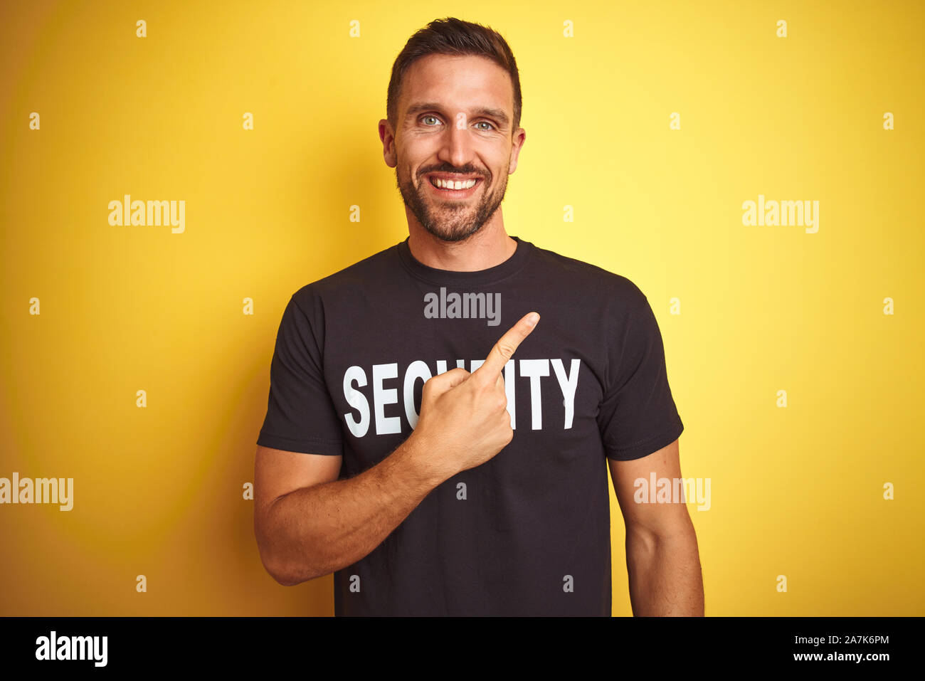 Young safeguard man wearing security uniform over yellow isolated ...