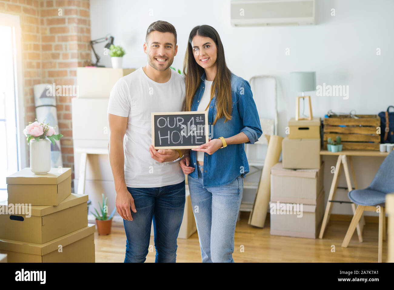 Beautiful young couple moving to a new house, smiling very happy ...