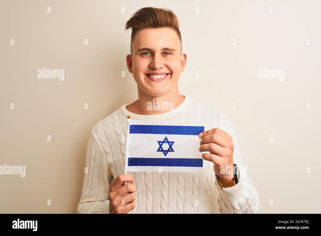 Young handsome man holding Israel Israeli flag over isolated white ...