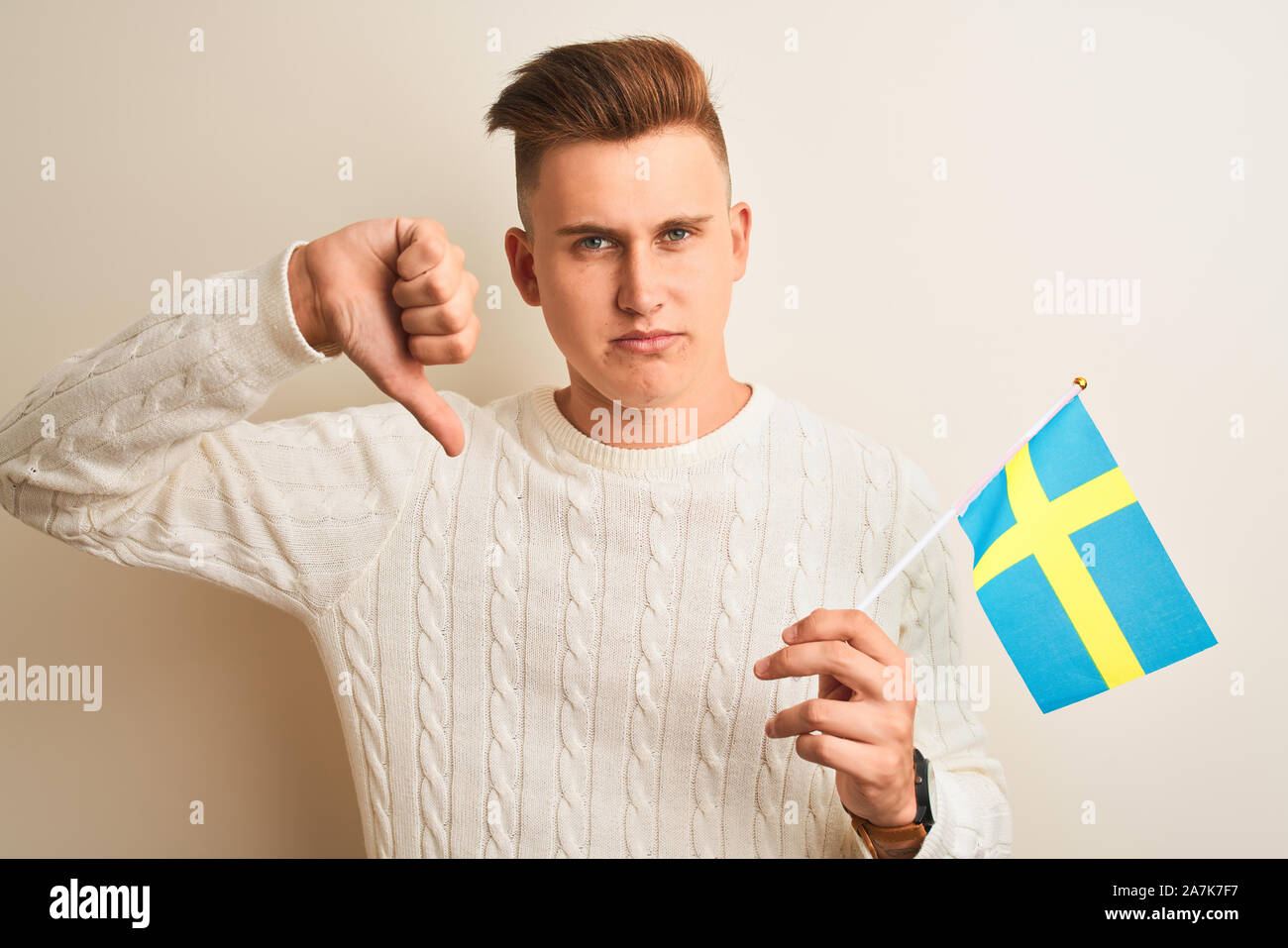 Young handsome man holding Sweadish Sweden flag over isolated white ...