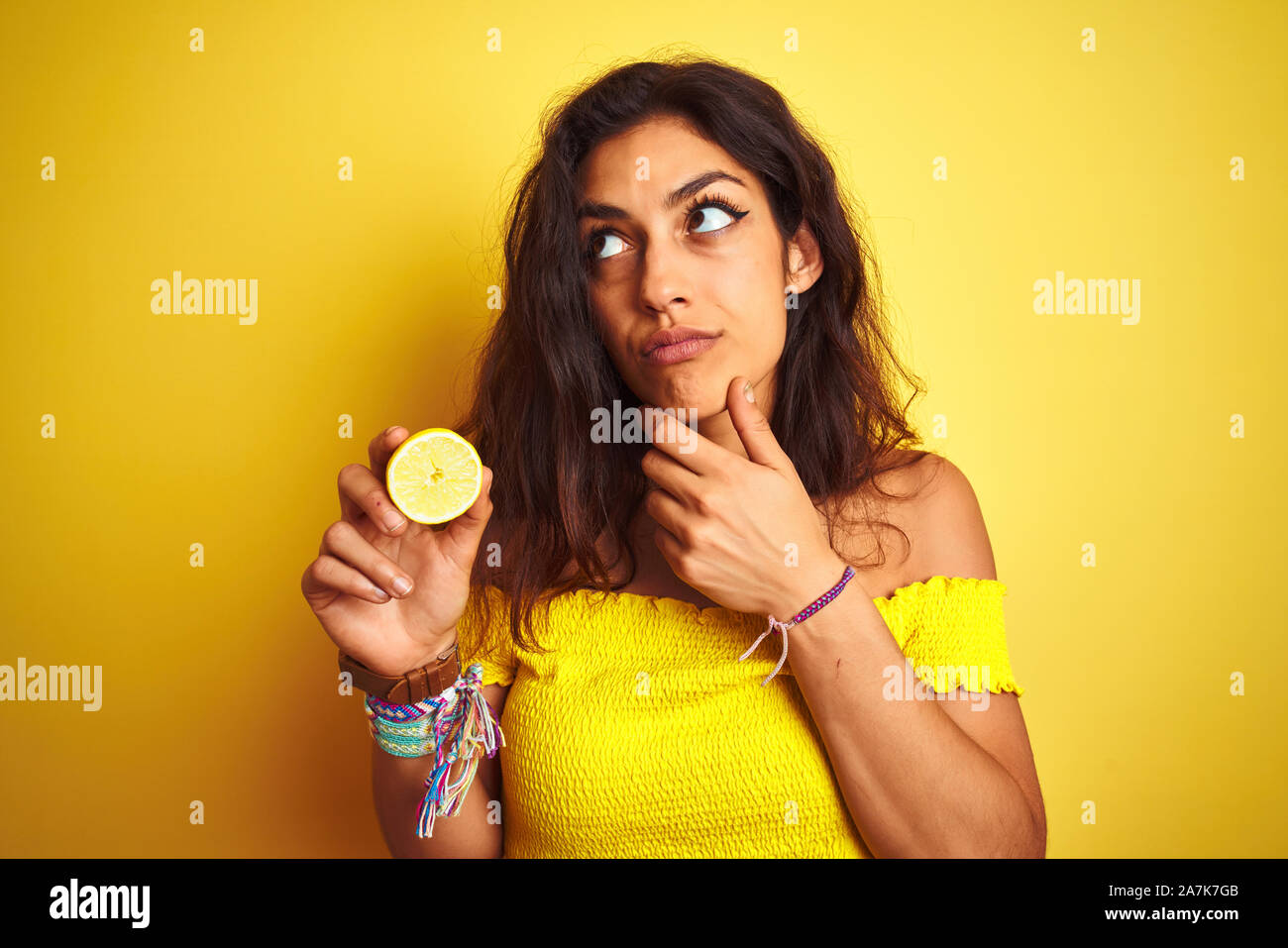 Young beautiful woman holding middle lemon standing over isolated ...
