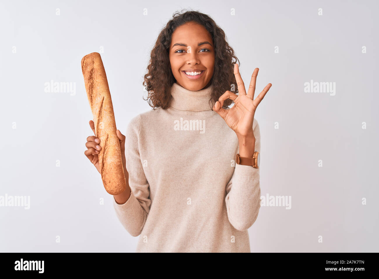 Young brazilian baker woman holding bread standing over isolated white ...