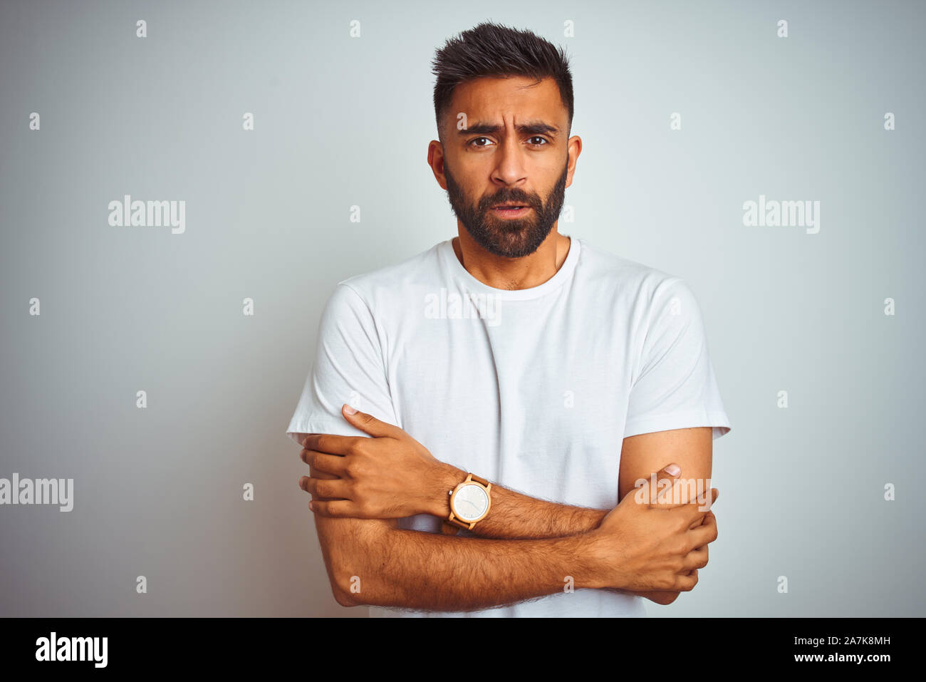 Young indian man wearing t-shirt standing over isolated white ...