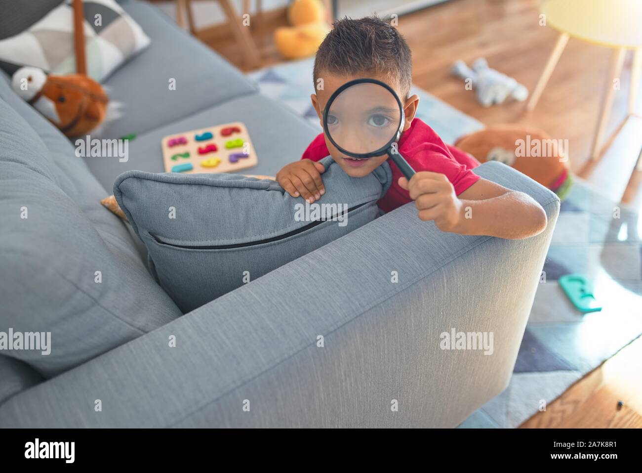 Adorable toddler playing using loupe around lots of toys at ...