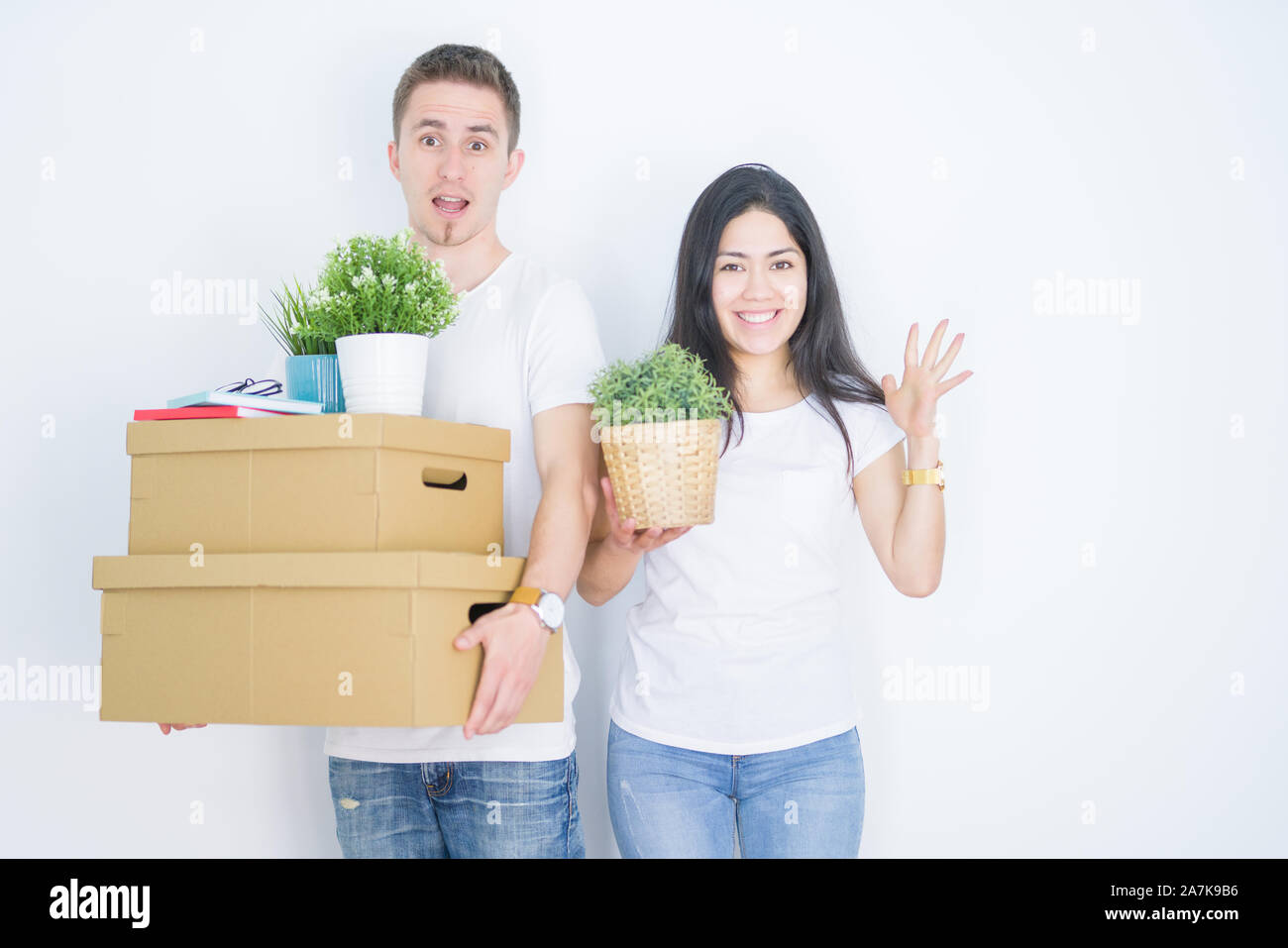 Young beautiful couple holding cardboard boxes standing over isolated ...