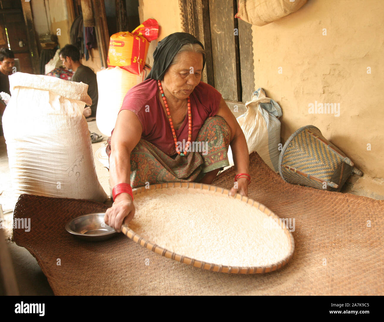 A Nepali woman dries out rice using a traditional method, Annapurna ...