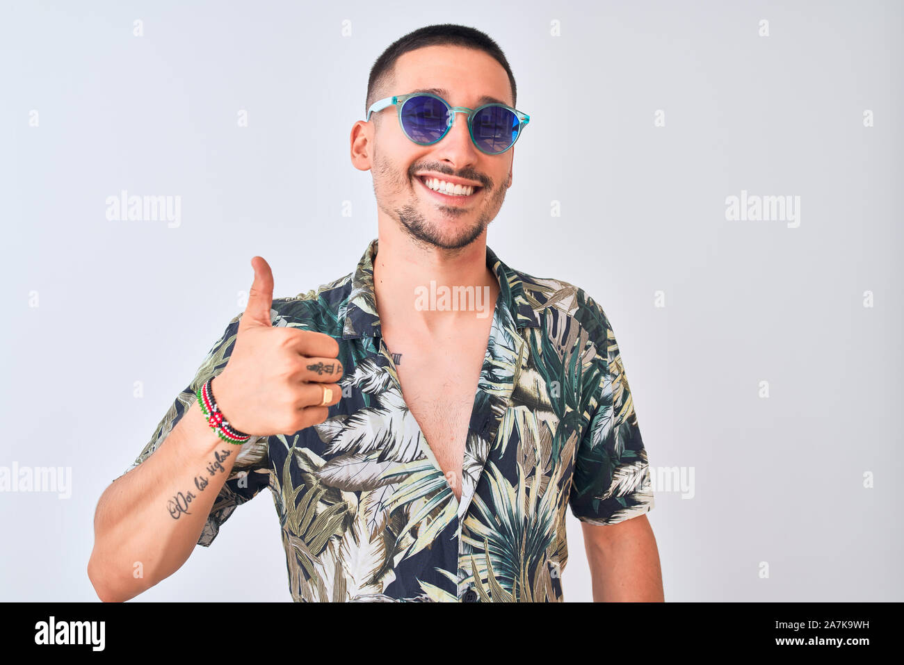 Young handsome man wearing Hawaiian sumer shirt and blue sunglasses ...