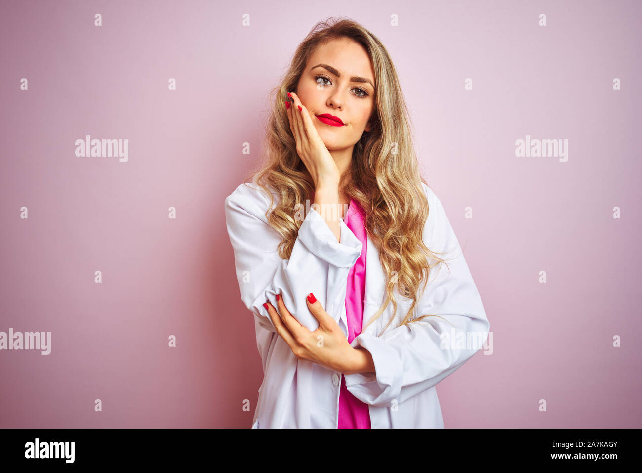 Young beautiful doctor woman standing over pink isolated background thinking looking tired and ...