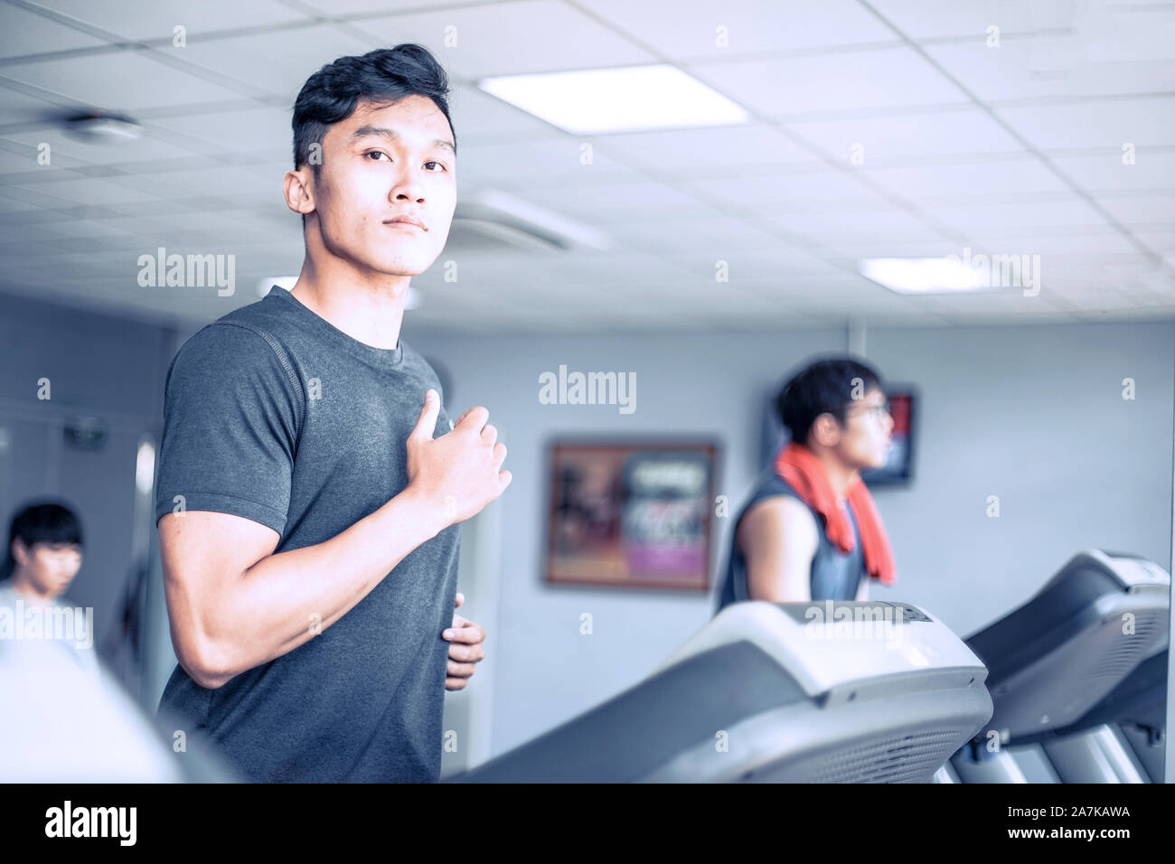 Handsome young atheletic man in sportswear running on treadmill at gym ...