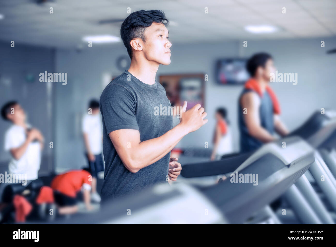 Asian young atheletic boy in sportswear running on treadmill at gym ...