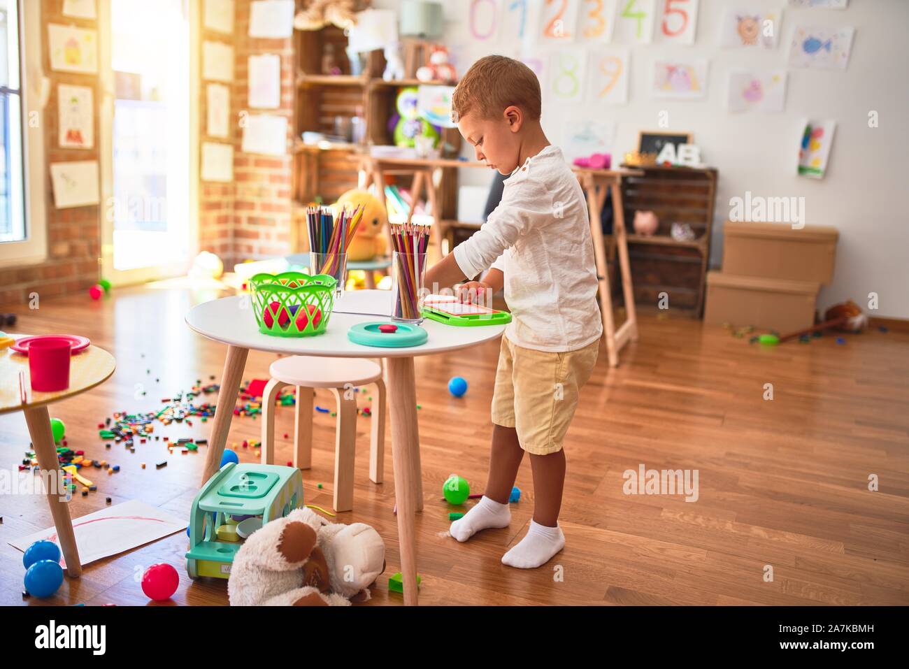 Beautiful blonde toddler drawing using digital board. Standing around ...