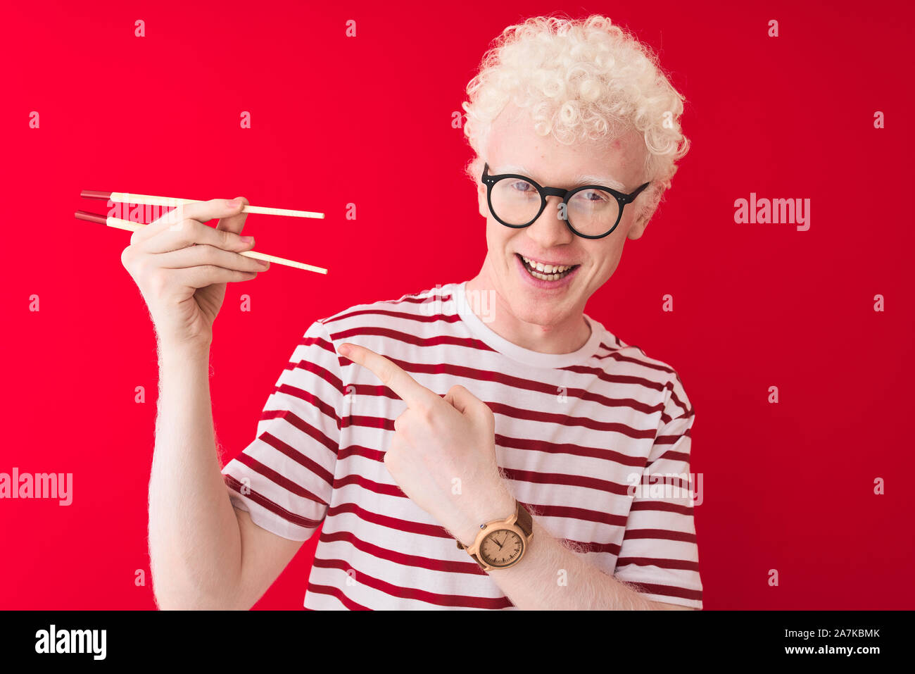 Young albino blond man holding chopsticks standing over isolated white ...