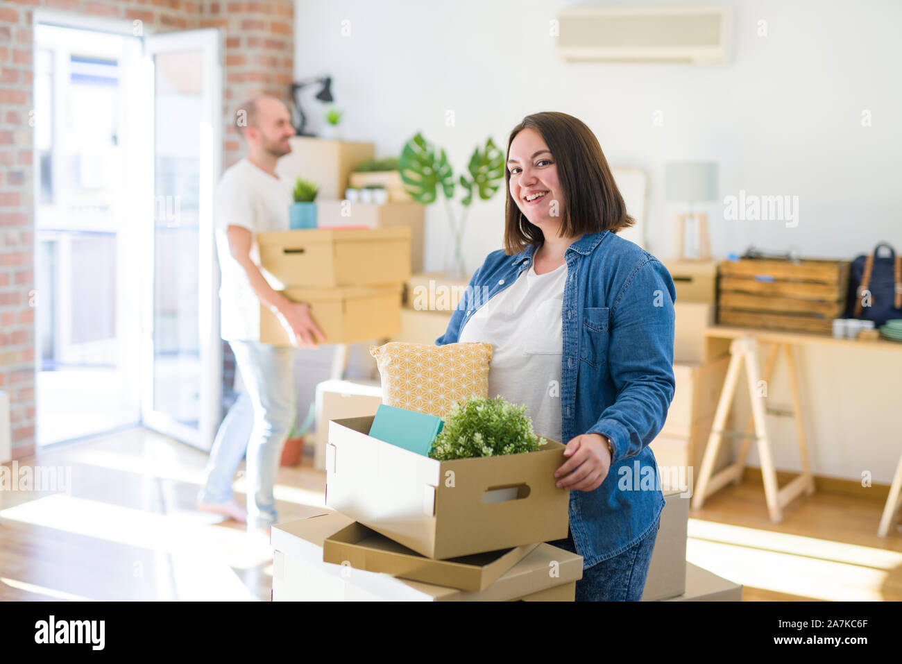 Young couple moving to new apartment, beautiful woman moving cardboard ...