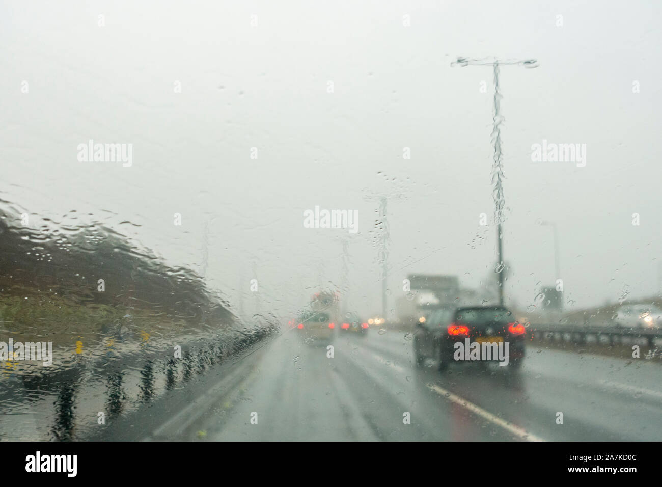 Cars on a motorway in the UK viewed through a rain covered windscreen ...
