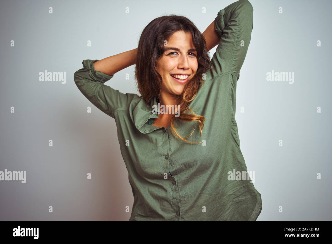 Young beautiful woman wearing green shirt standing over grey isolated ...