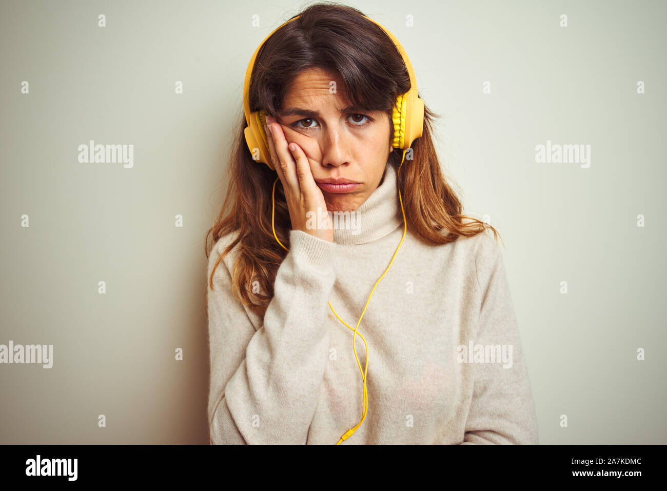 Young beautiful woman listening to music using headphones over white ...