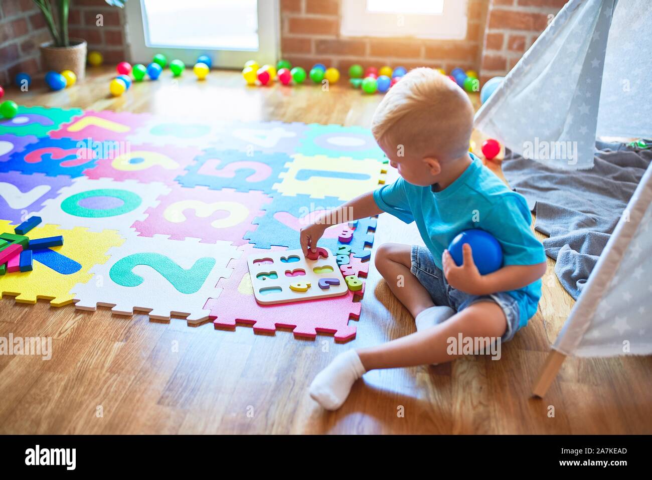 Young caucasian kid playing placing numbers at kindergarten ...