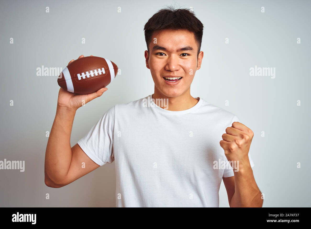 Young asian chinese sportsman holding rugby ball standing over isolated ...