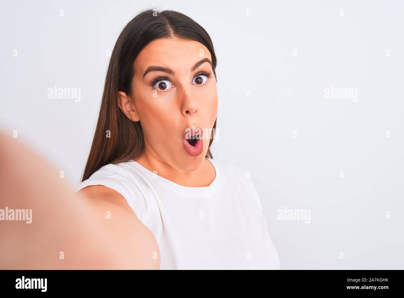 Beautiful young woman taking a selfie photo using smartphone over white ...