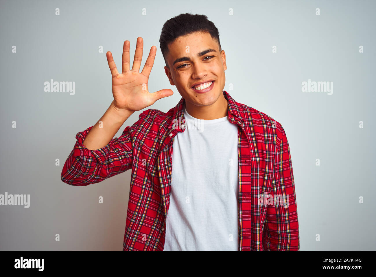 Young brazilian man wearing red shirt standing over isolated white ...