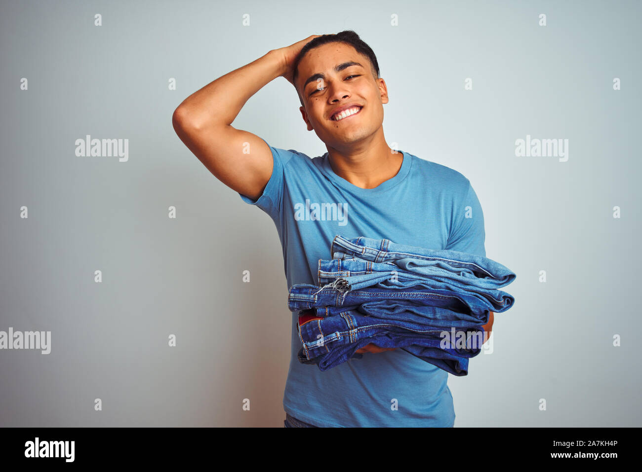 Young brazilian shopkeeper man holding jeans standing over isolated ...