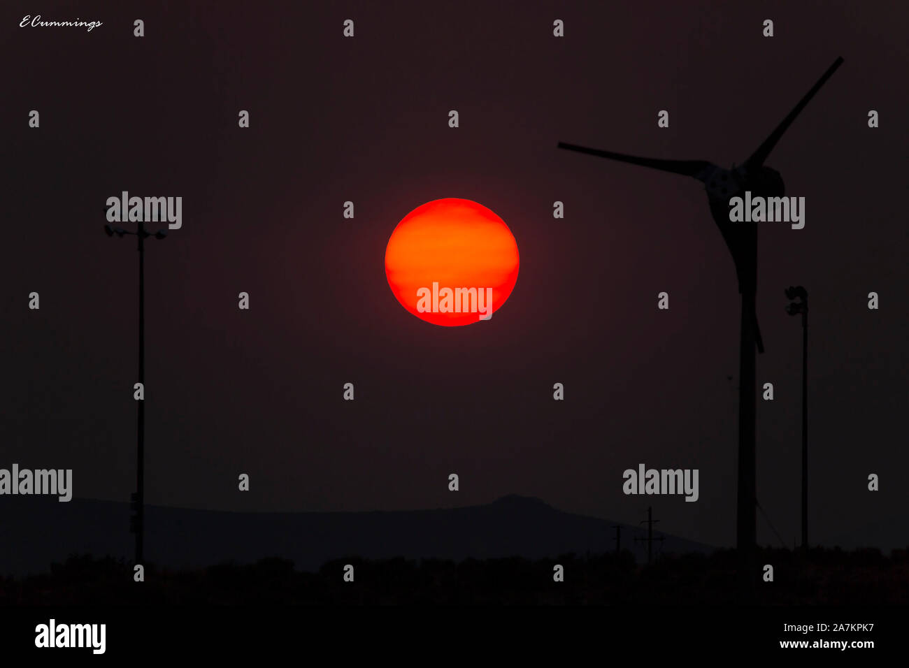 Red smoky sun setting near windmills during wildfire season Stock Photo ...