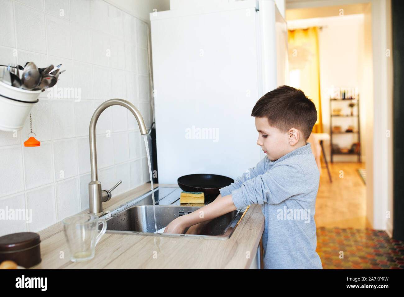 Little cute boy washing dishes in kitchen interior. Child with helping ...