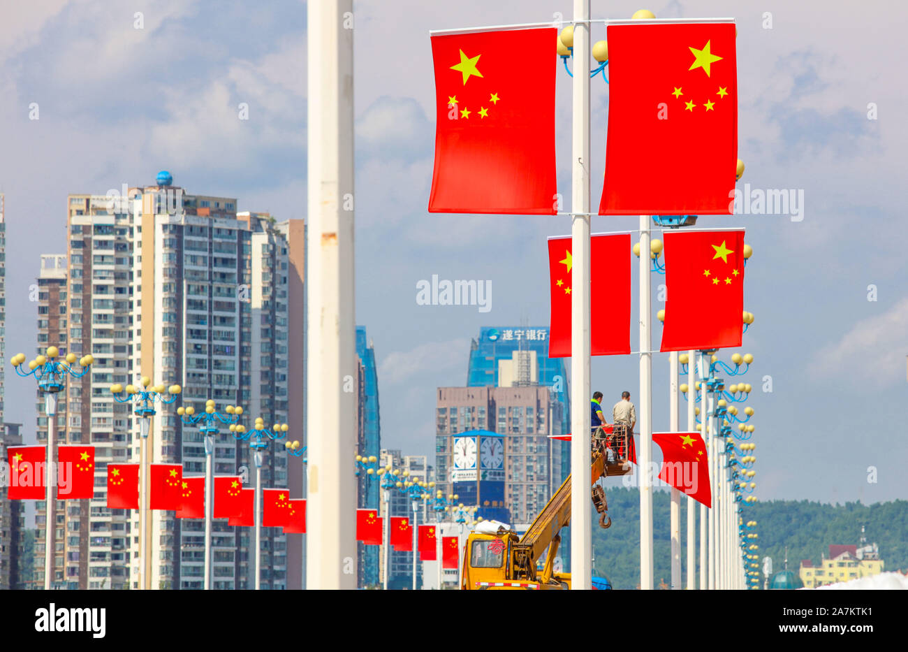 Workers hang national flags in streets to celebrate the 70th National ...